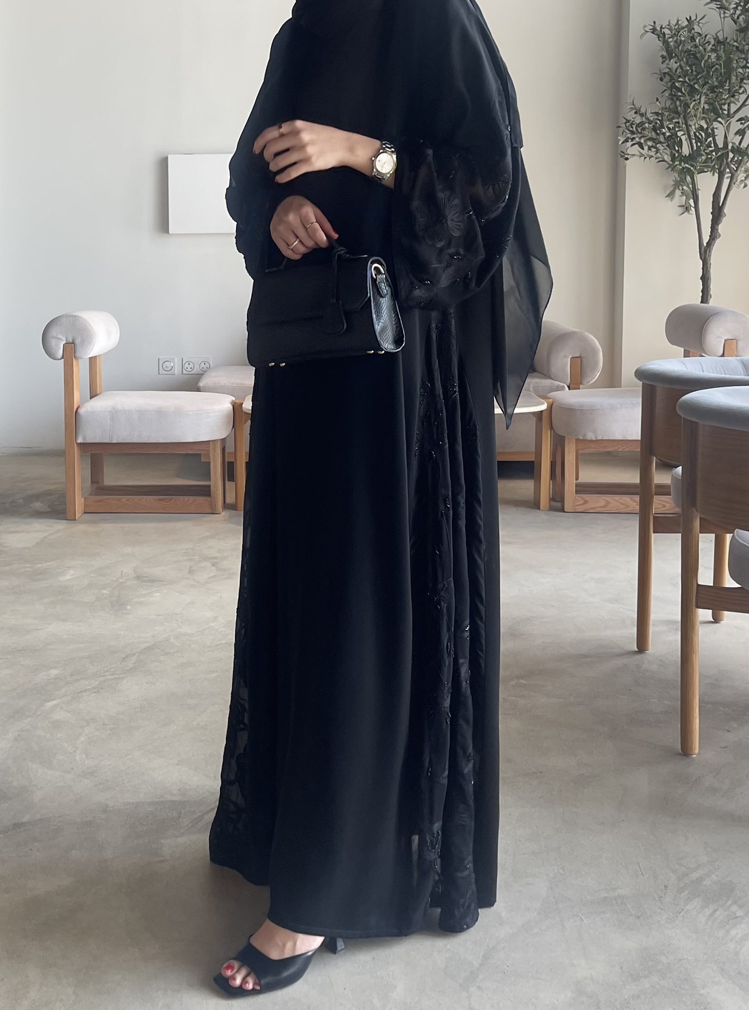 S044 Noir Nada Abaya, featuring exquisite chiffon embellishments cascading along the sleeves and ...